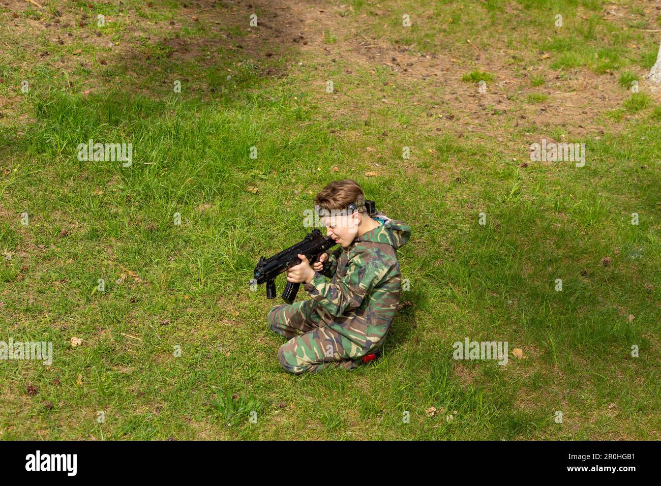 Boy weared in camouflage playing laser tag in special forest playground ...