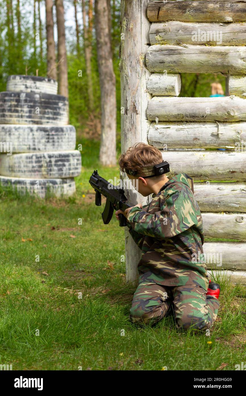 Boy weared in camouflage playing laser tag in special forest playground ...