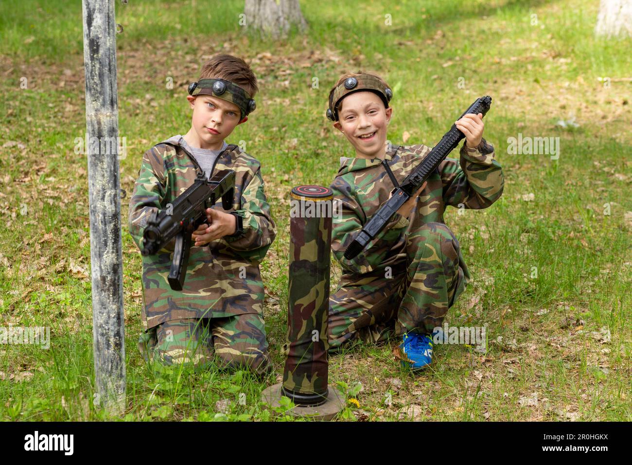 Two boys weared in camouflage playing laser tag in special forest ...