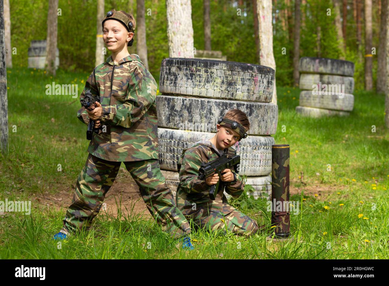 Two boys weared in camouflage playing laser tag in special forest ...