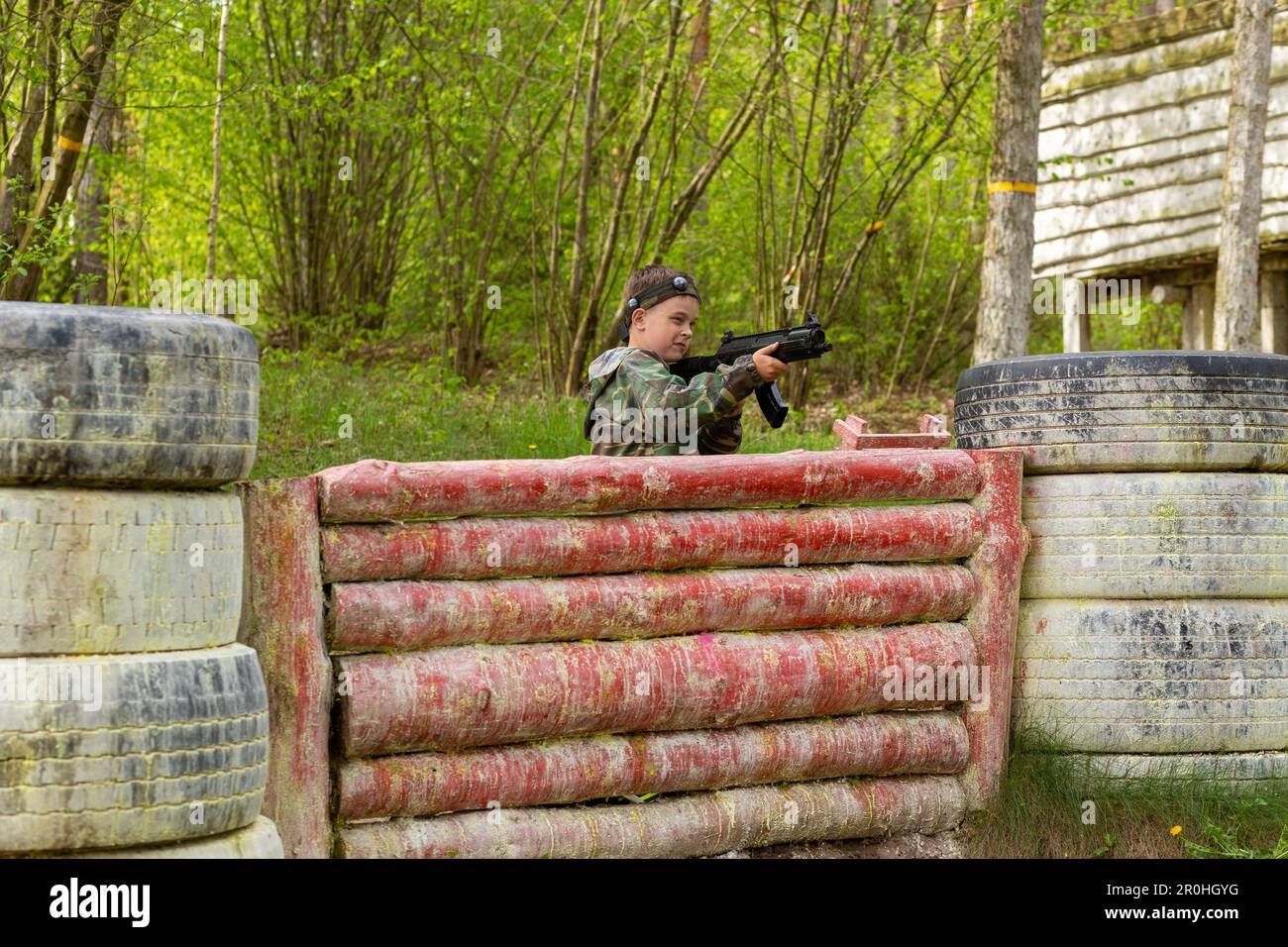 Boy weared in camouflage playing laser tag in special forest playground ...