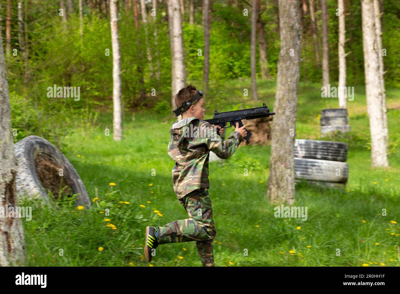 Boy weared in camouflage playing laser tag in special forest playground ...