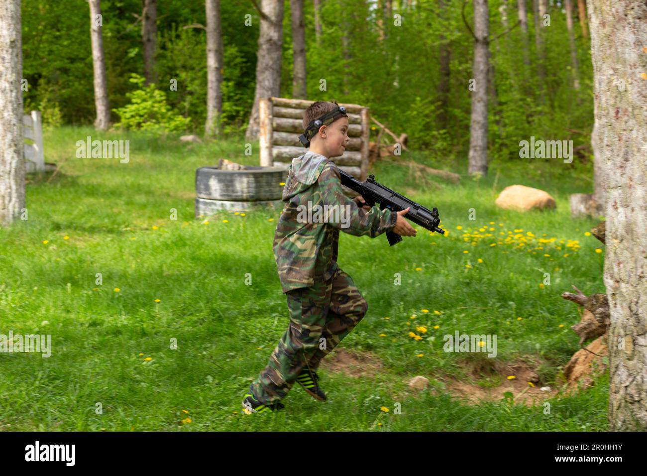 Boy weared in camouflage playing laser tag in special forest playground ...