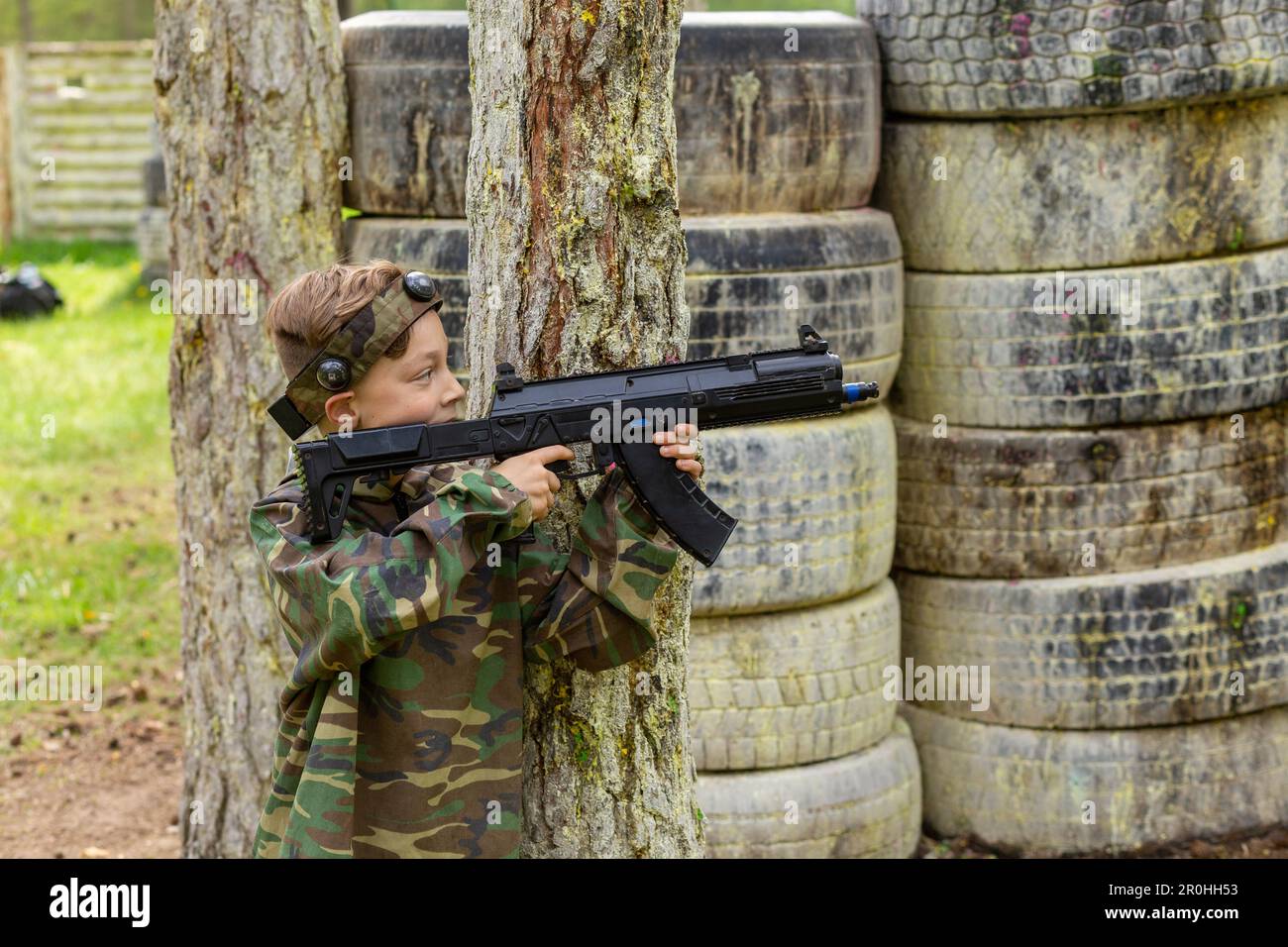 Boy weared in camouflage playing laser tag in special forest playground ...