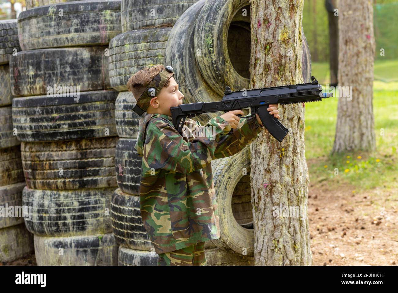 Boy weared in camouflage playing laser tag in special forest playground ...