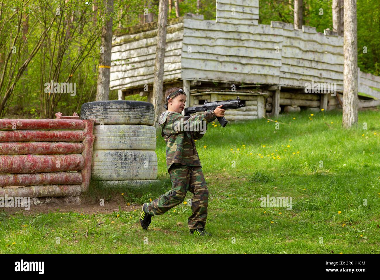 Boy weared in camouflage playing laser tag in special forest playground ...