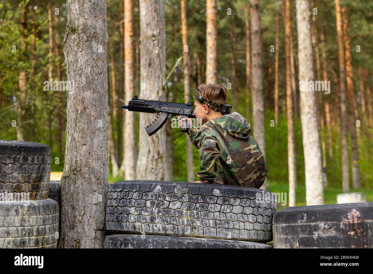 Boy weared in camouflage playing laser tag in special forest playground ...