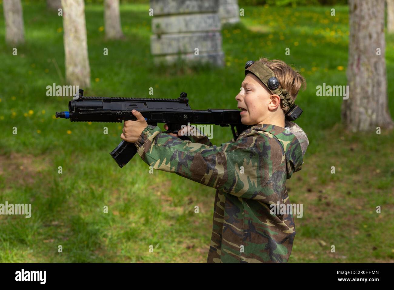 Boy weared in camouflage playing laser tag in special forest playground ...
