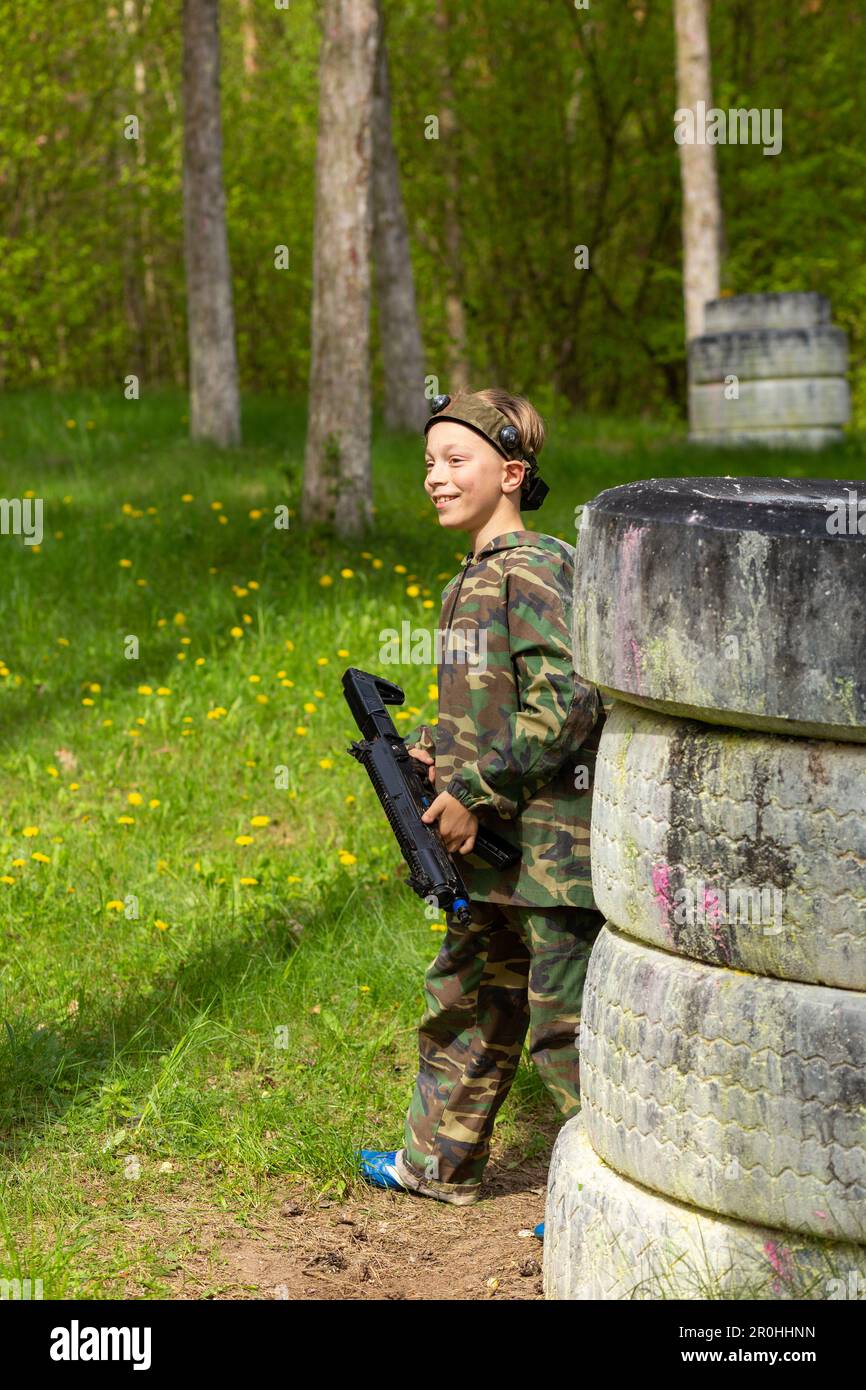 Boy weared in camouflage playing laser tag in special forest playground ...