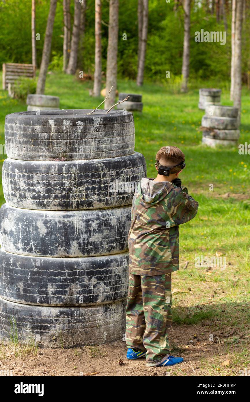 Boy weared in camouflage playing laser tag in special forest playground ...