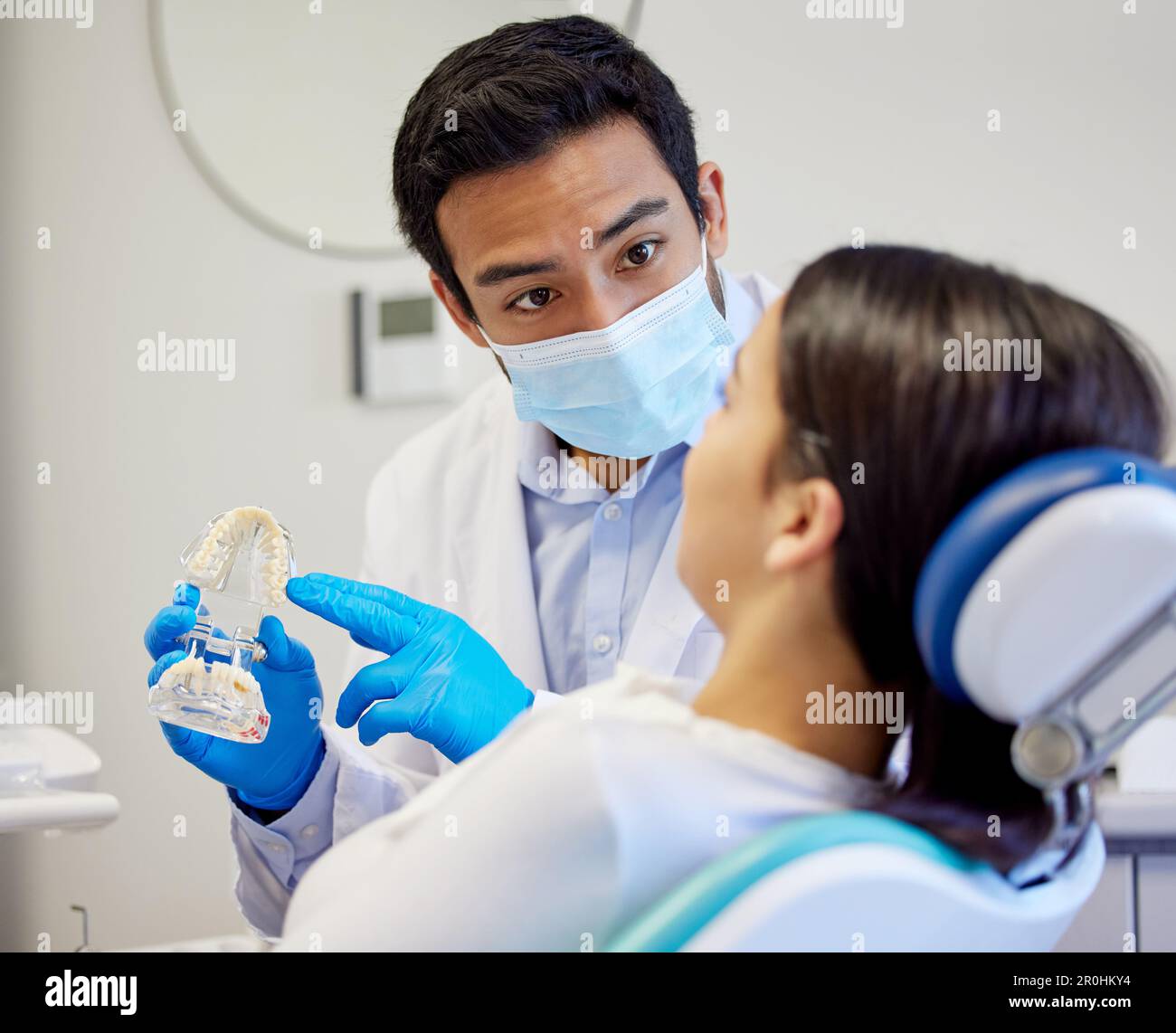 We may need to extract a tooth. a dentist showing his patient a model ...