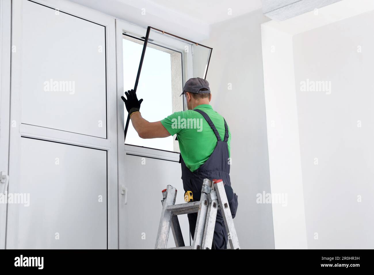 Worker on folding ladder installing window indoors Stock Photo - Alamy