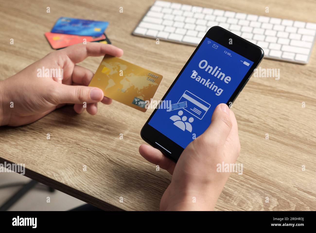 Man using online banking app on smartphone and credit card at wooden ...