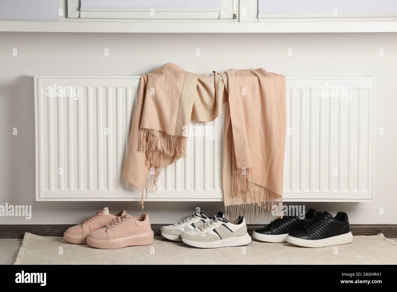 Heating radiator with scarf and shoes near window in room Stock Photo ...