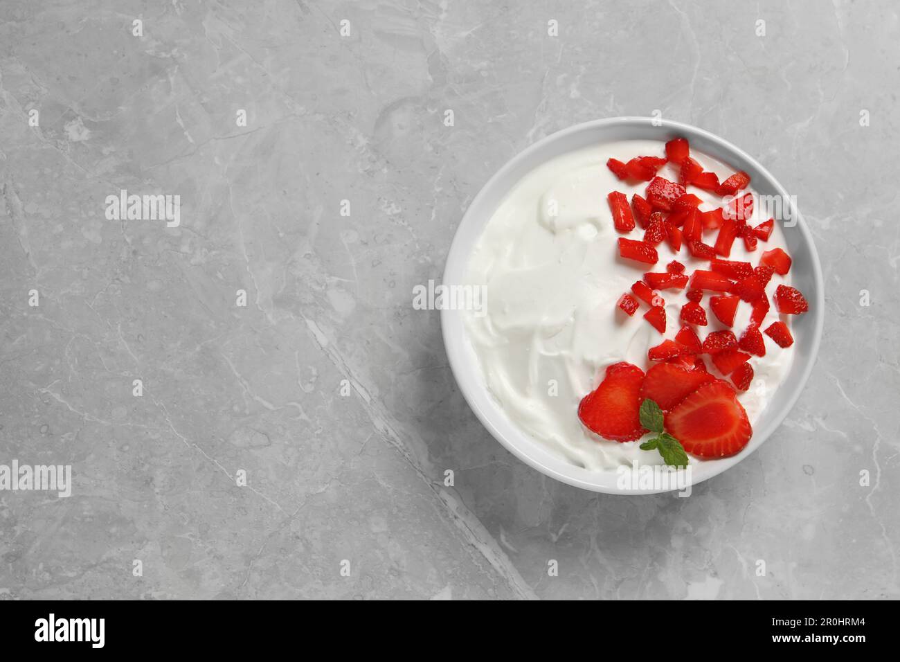 Delicious yogurt served with strawberries on grey marble table, top ...