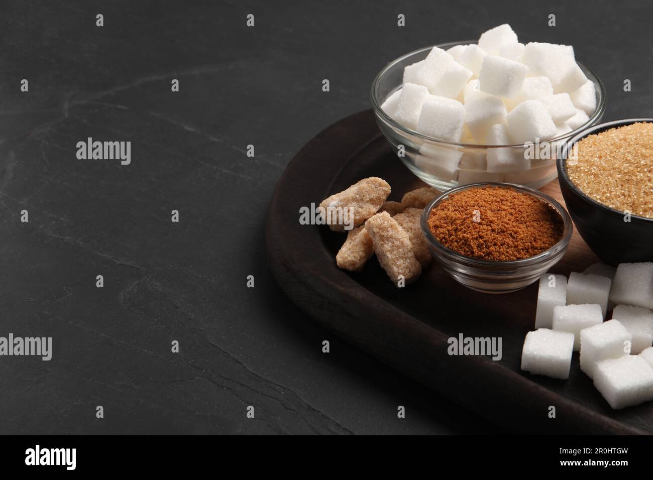 Different types of sugar on black table, closeup. Space for text Stock ...