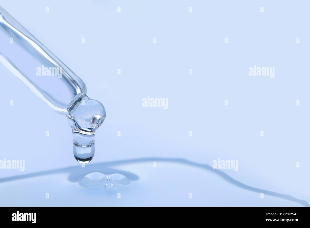 Dripping face serum from pipette on white background, closeup. Space ...