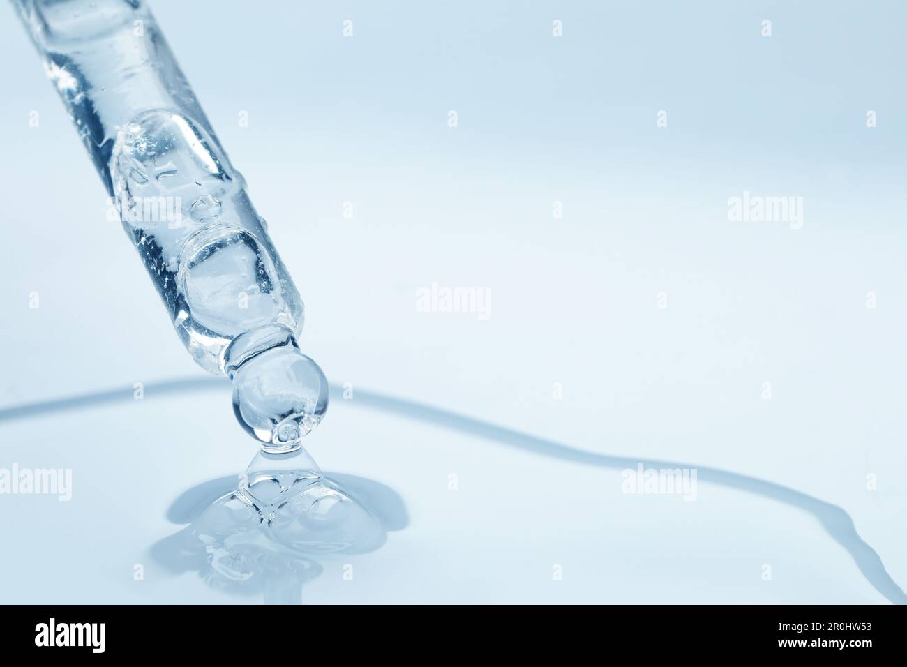 Dripping face serum from pipette on white background, closeup. Space ...
