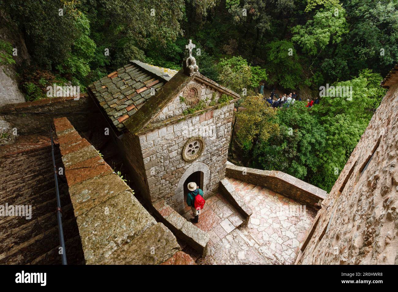 Hiker, pilgrim visiting the chapel Eremo delle Carceri, hermitage above ...