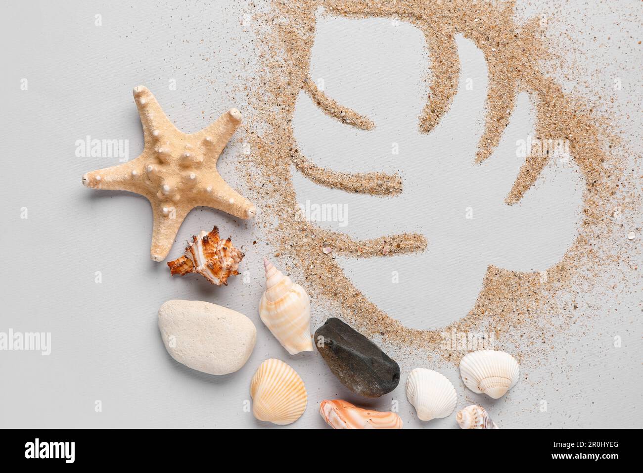 Palm leaf made of sand with starfishes and seashells on grey background ...