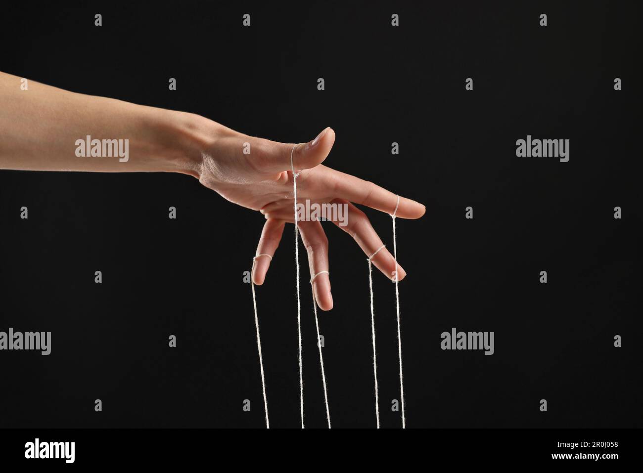 Woman pulling strings of puppet on black background, closeup Stock ...