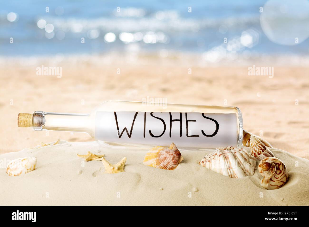 Corked glass bottle with rolled paper note and seashells on sandy beach ...