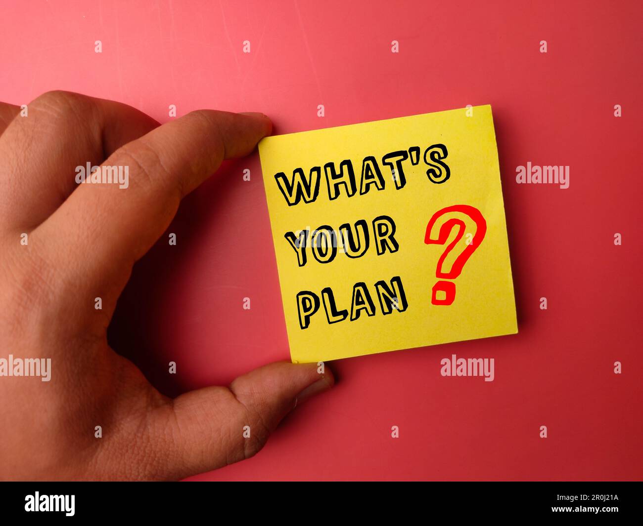 Hand holding sticky note with the word WHAT YOUR PLAN on a red ...