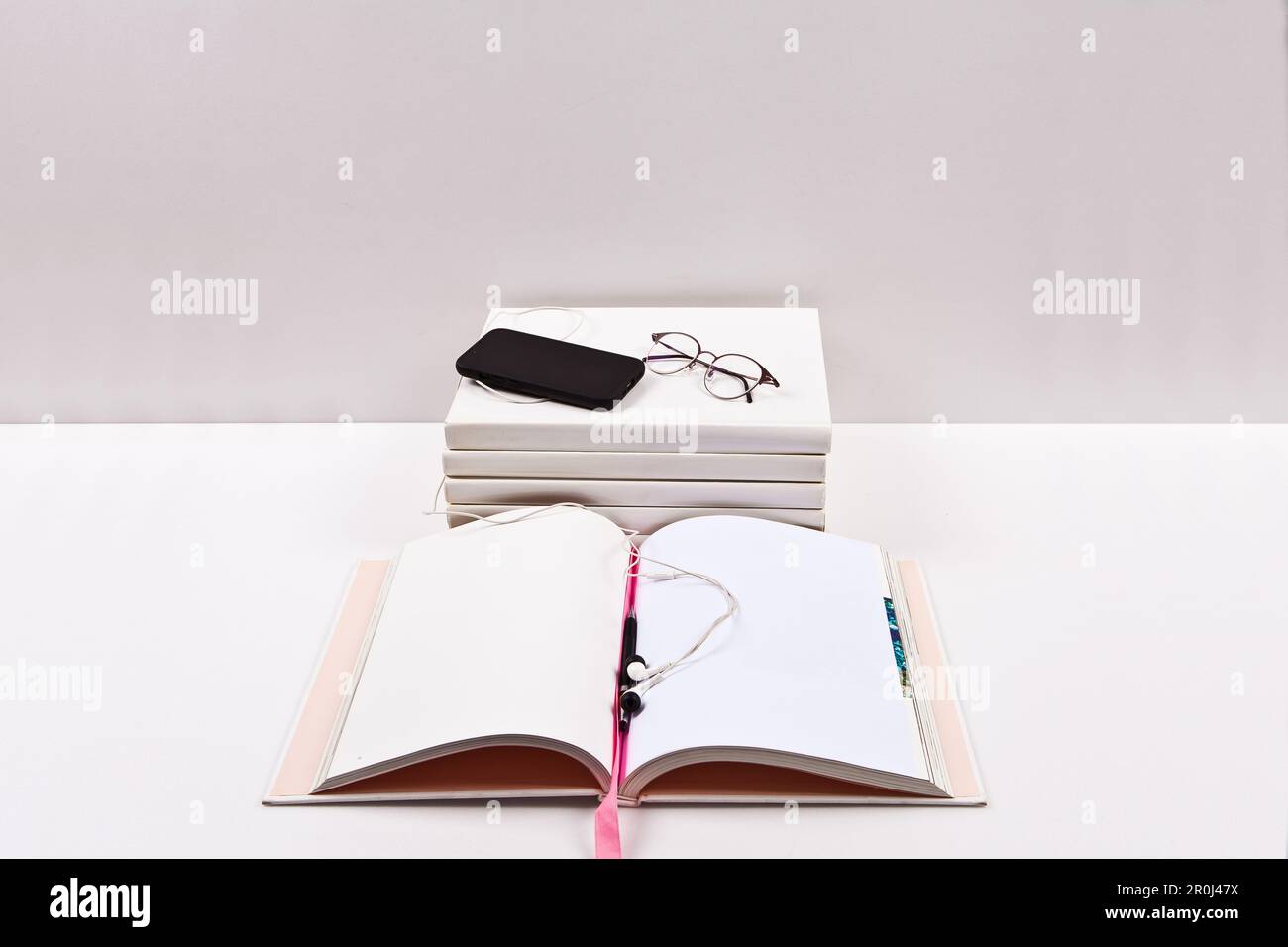 Notebook with smart phone and glasses on the table. White background ...