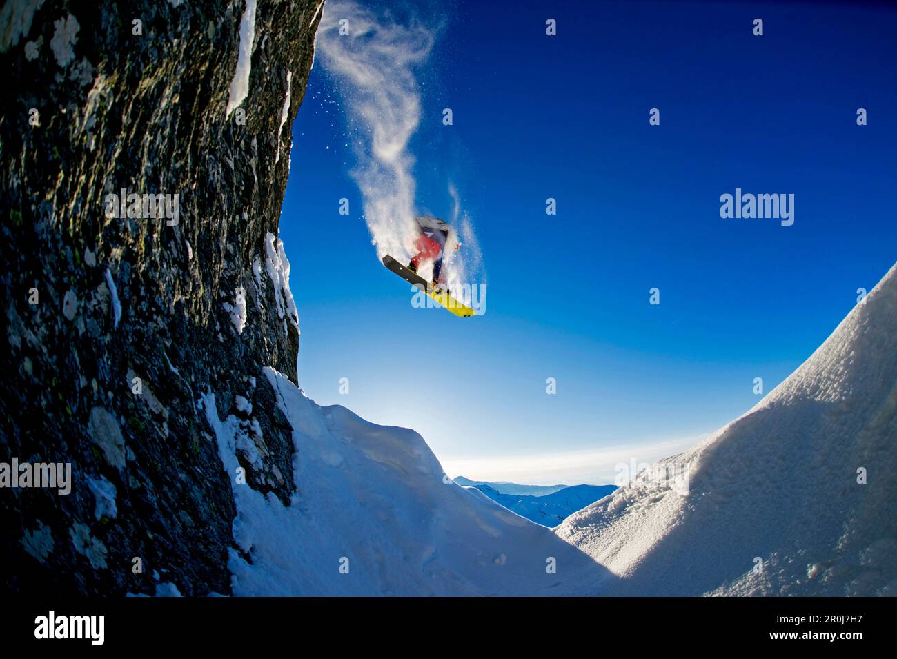 Snowboarder doing a back flip over rocks, Hochfuegen, Zillertal ...