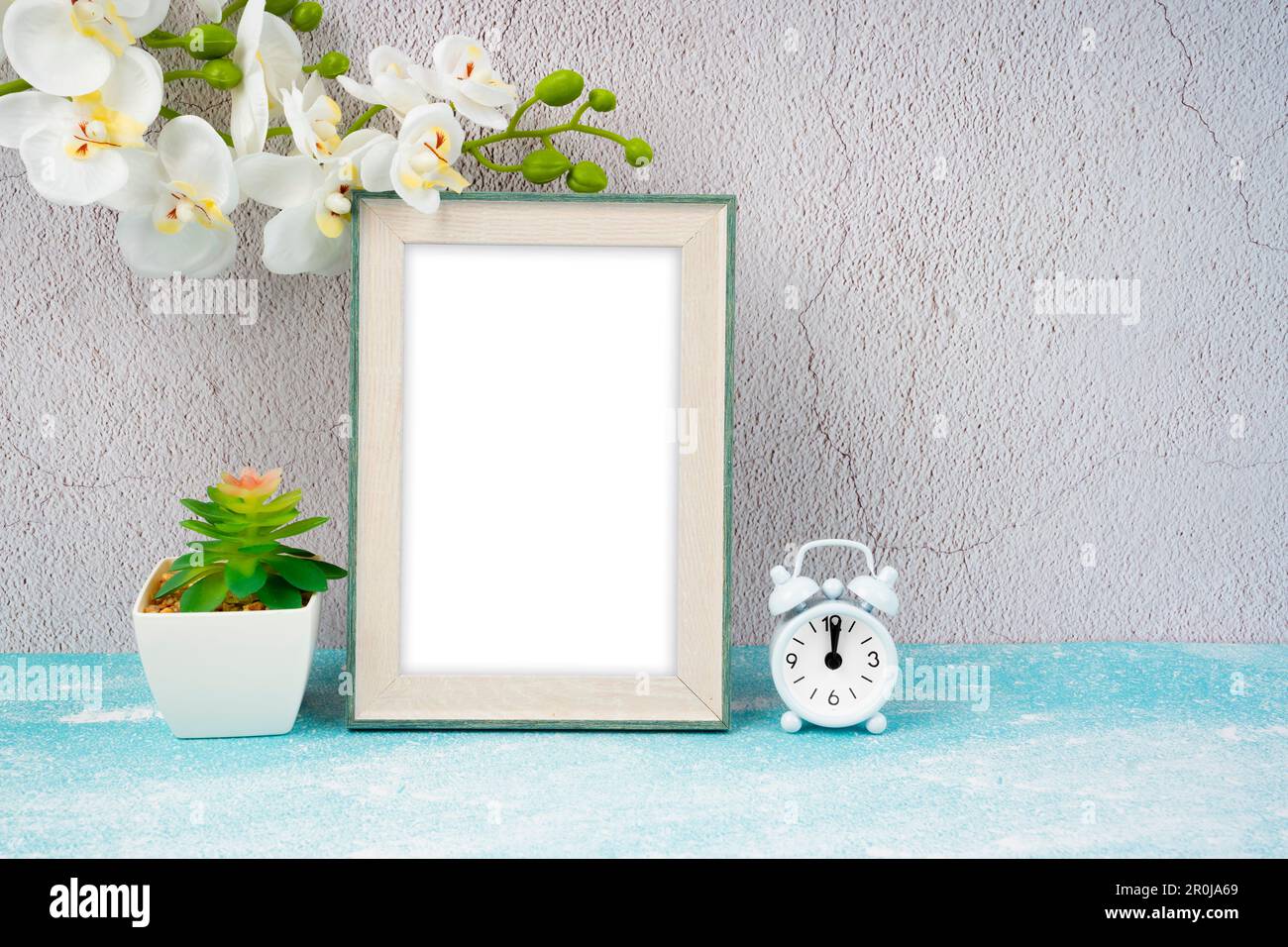 Blank picture frame and alarm clock on blue floor with copy space and ...