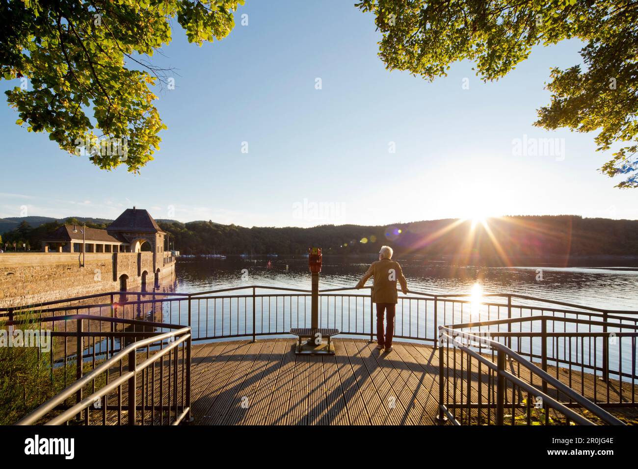 Man standing on a viewing platform in the light of the setting sun ...