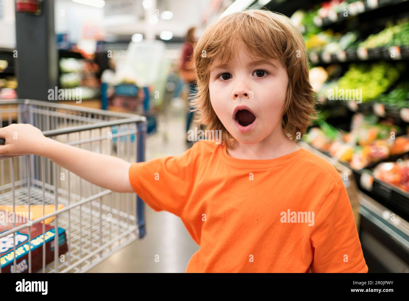 Funny shopping. Joyful beautiful child boy in supermarket buys ...