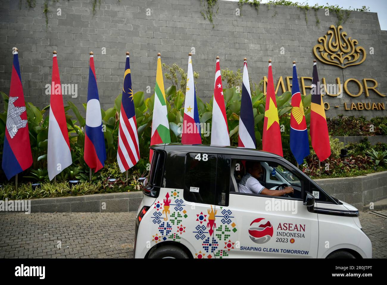 An electric vehicle moves past the flags of countries attending the ...