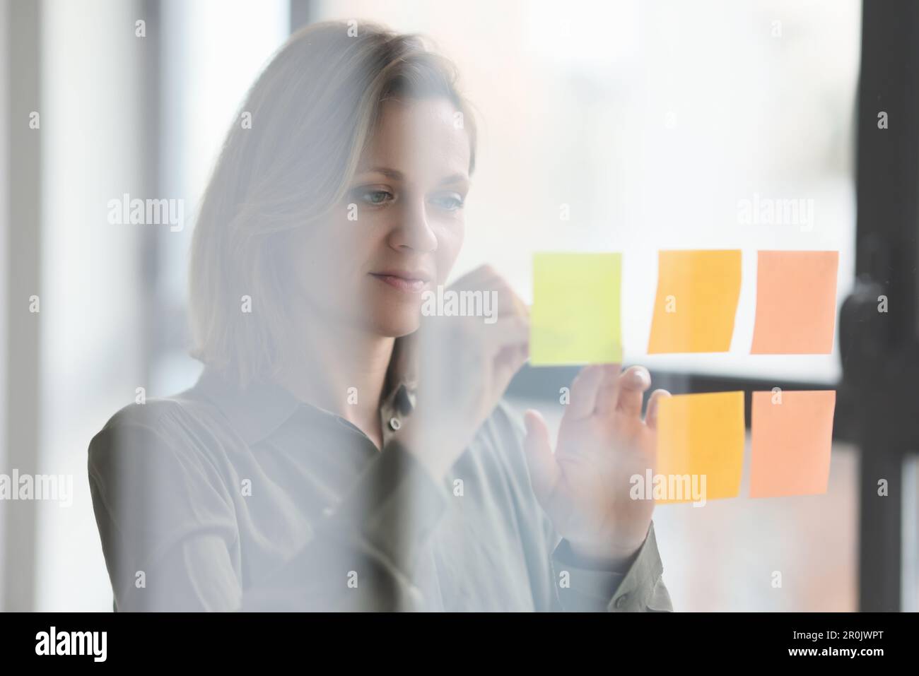 Manager putting stickers note on transparent glass wall in office Stock ...