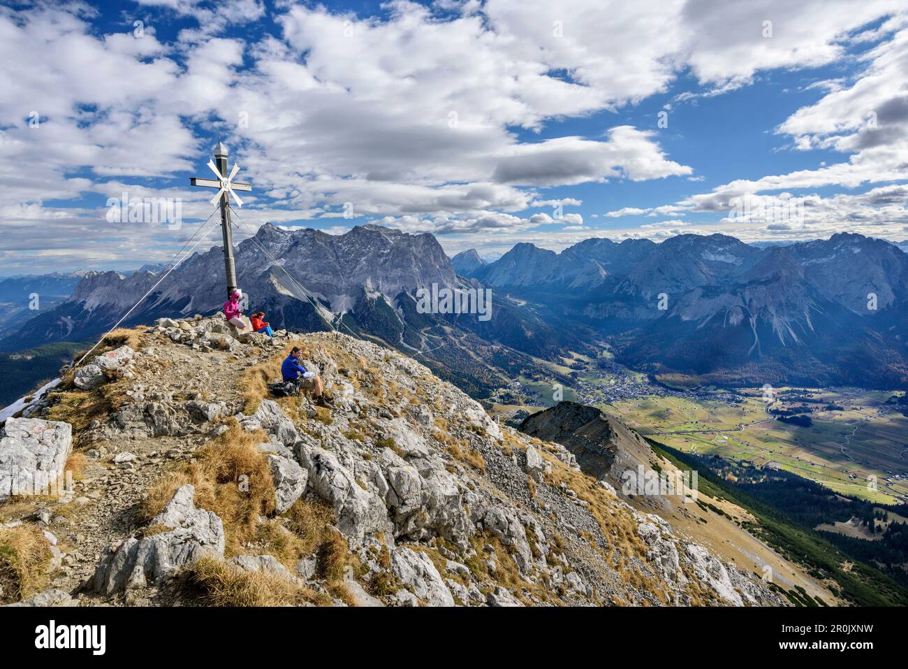 Several persons sitting at summit of Daniel, Zugspitze, valley of ...