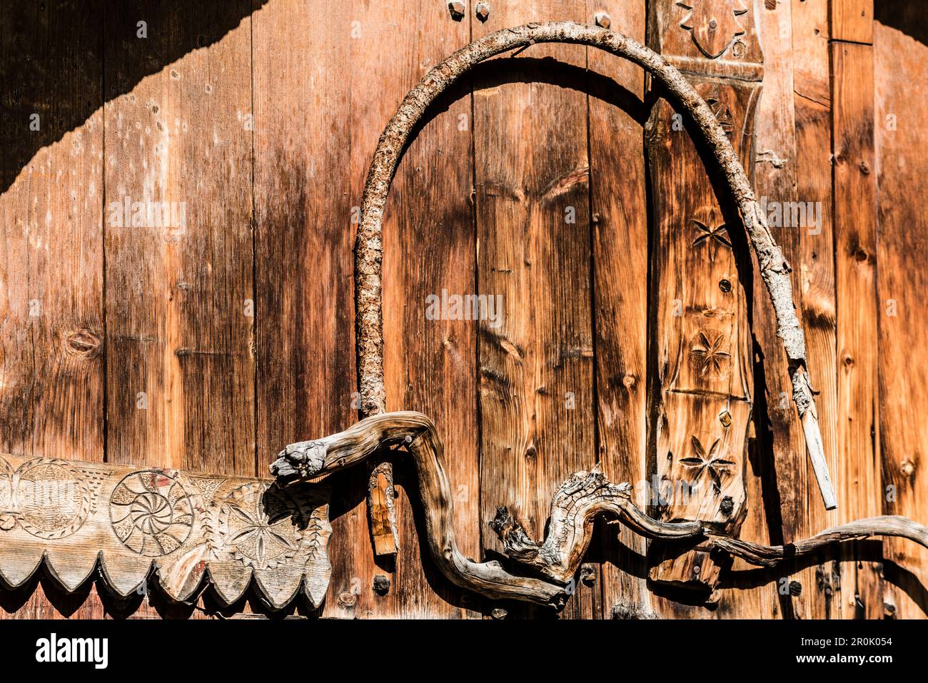 A wooden hut in the Alps, decorated with carvings and wooden stick look ...