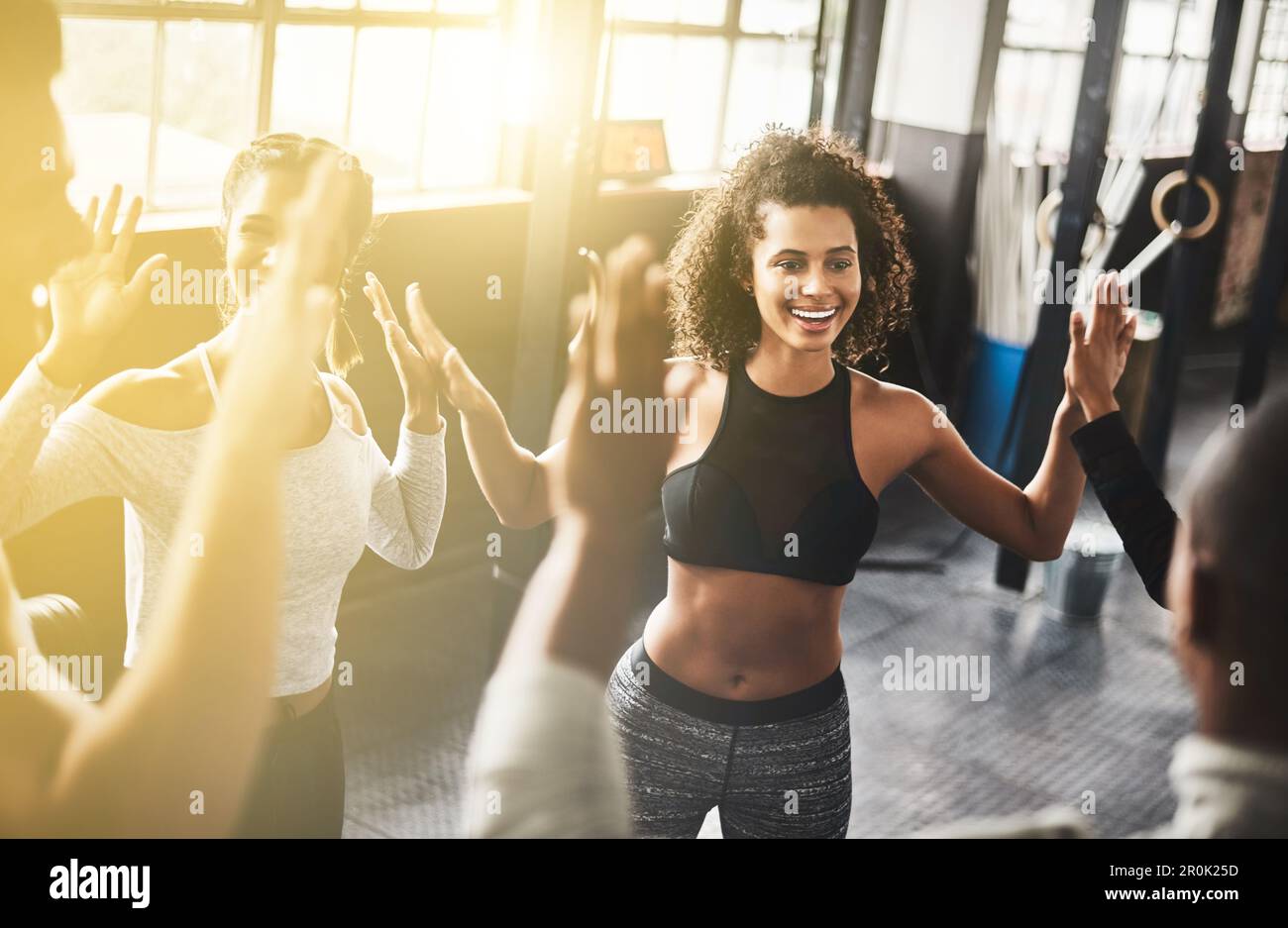 Funny, high five and collaboration of people in gym for fitness, team building and solidarity ...