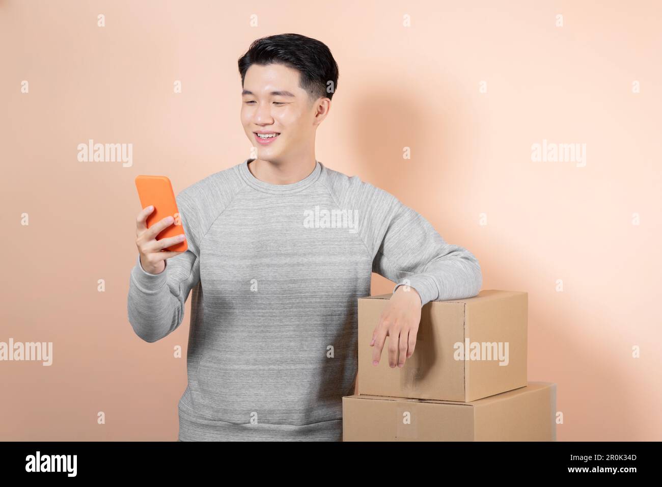 E-commerce male business owner using phone and holding packages in ...