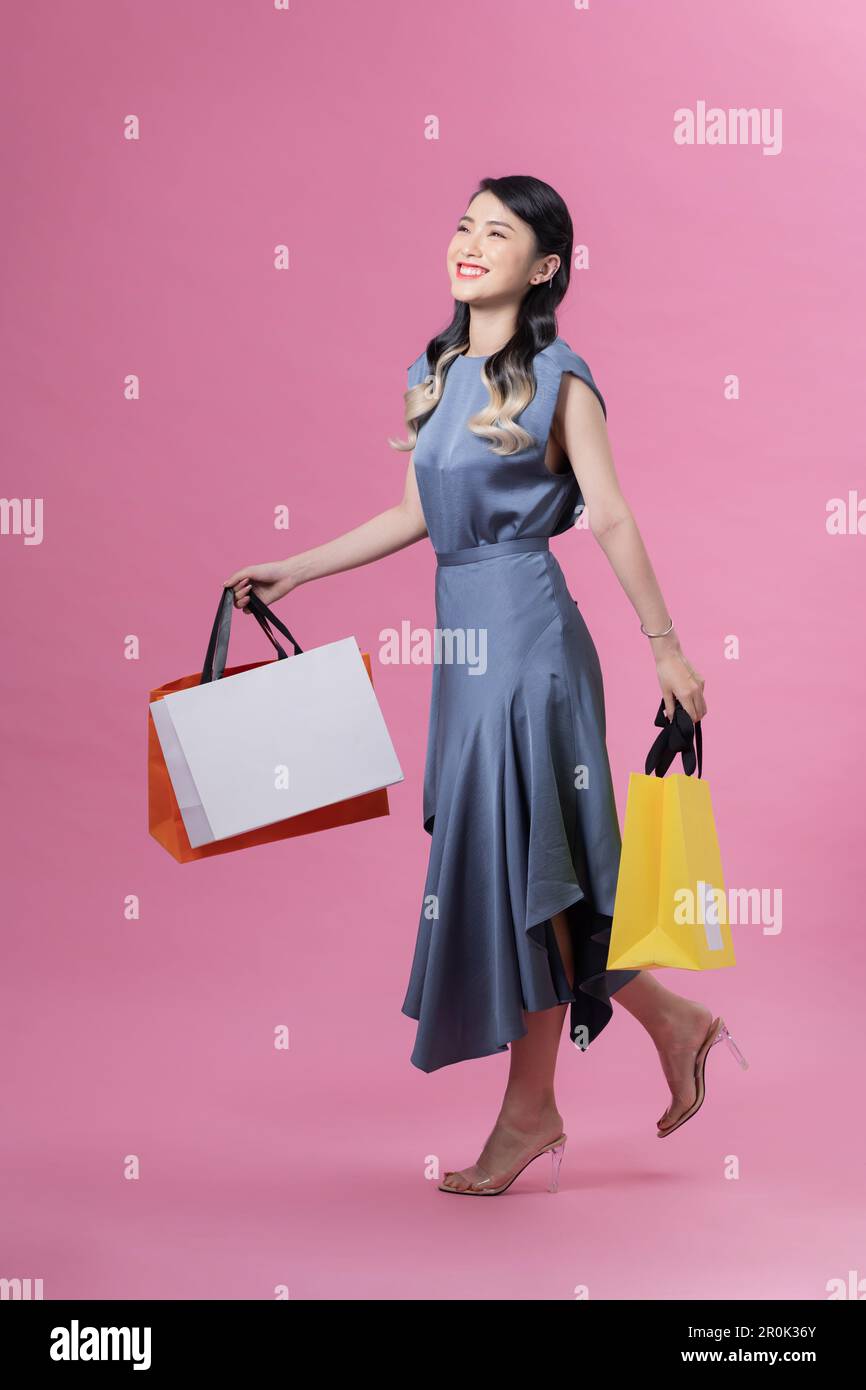 Attractive Smiling Vietnamese Woman Wearing High Heels And Blue Dress Walking With Paper Bags