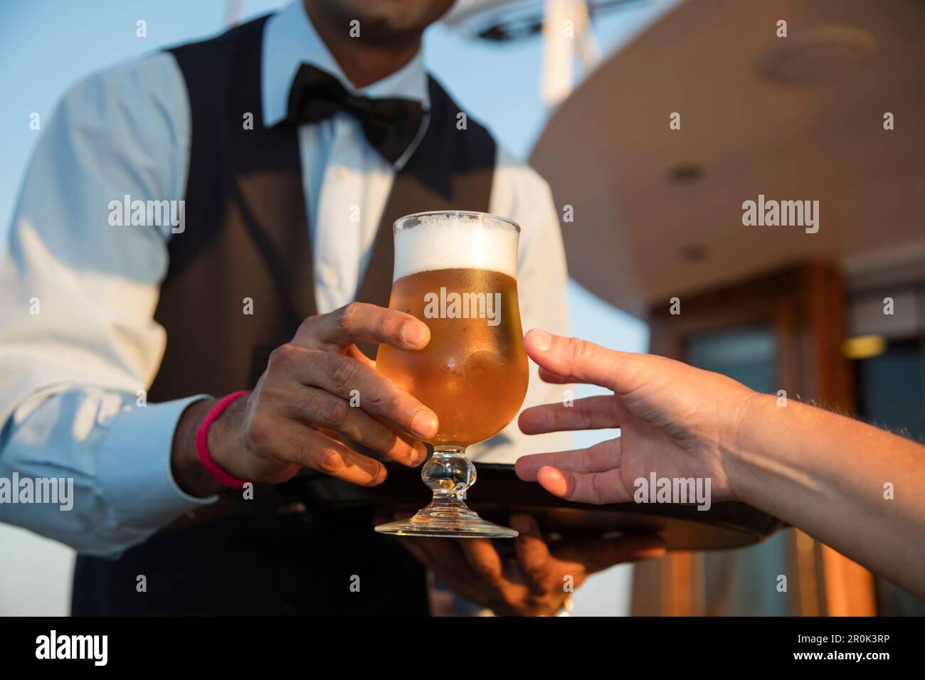 Glass of cold beer is served by bar steward aboard motor sailing cruise ...