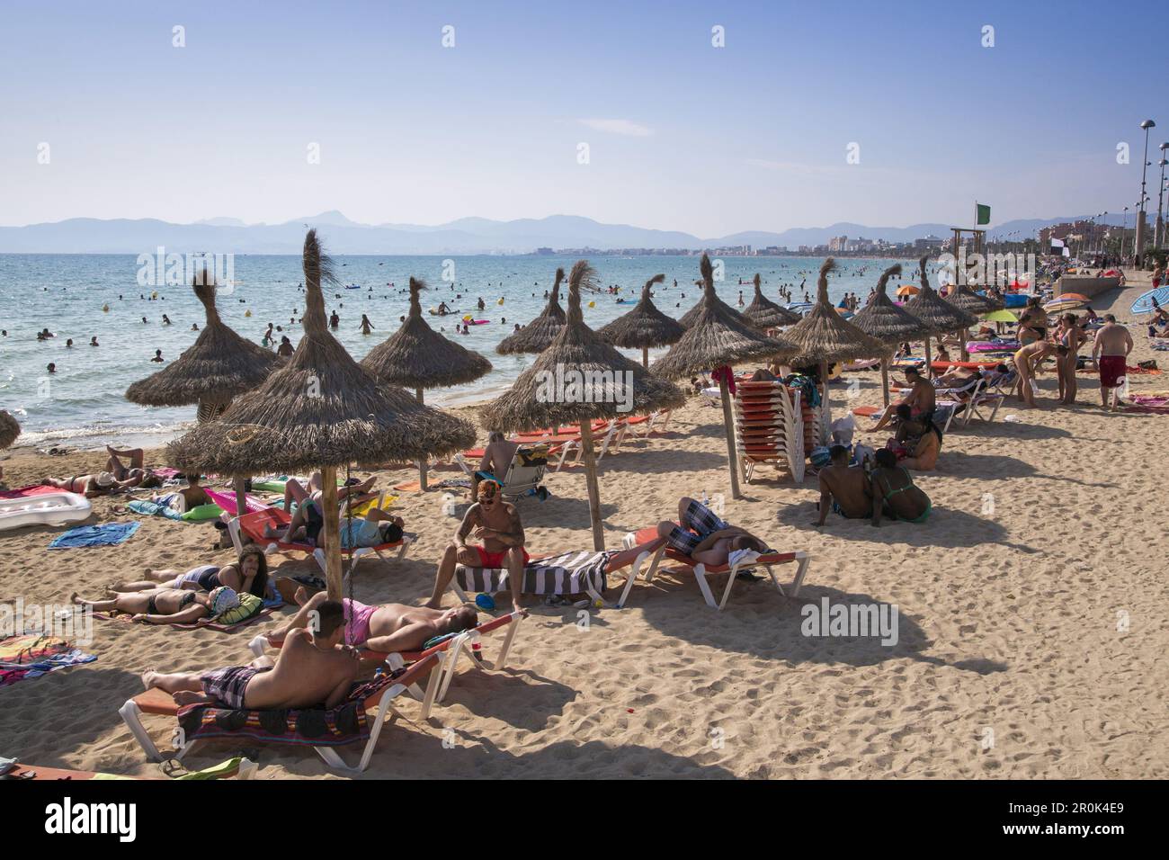 People relax under thatched umbrellas at Playa s'Arenal beach, s'Arenal ...