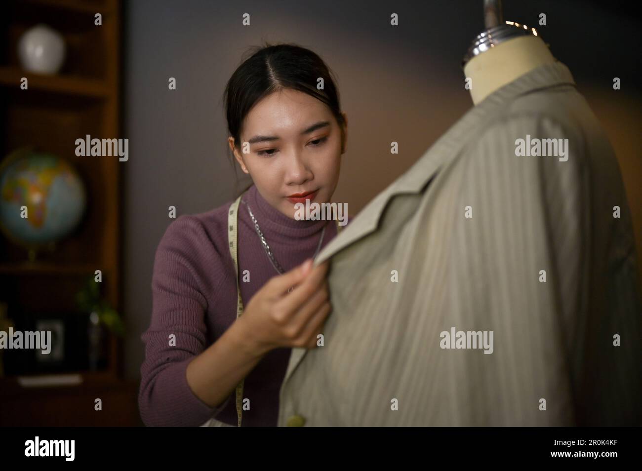 A beautiful young Asian female fashion designer checking fabric on her ...