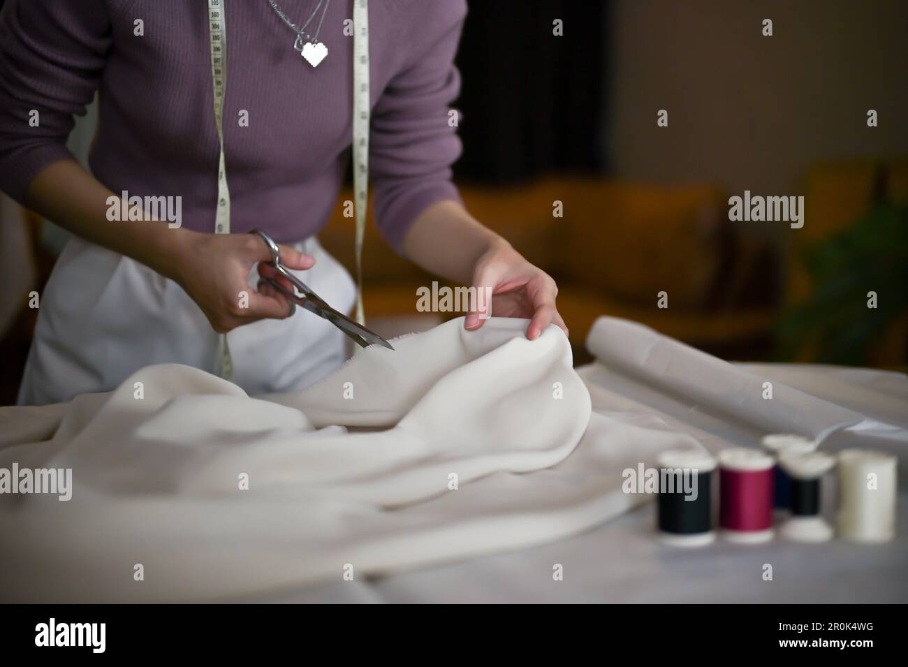 Close-up image of a dressmaker or fashion designer using scissors to ...
