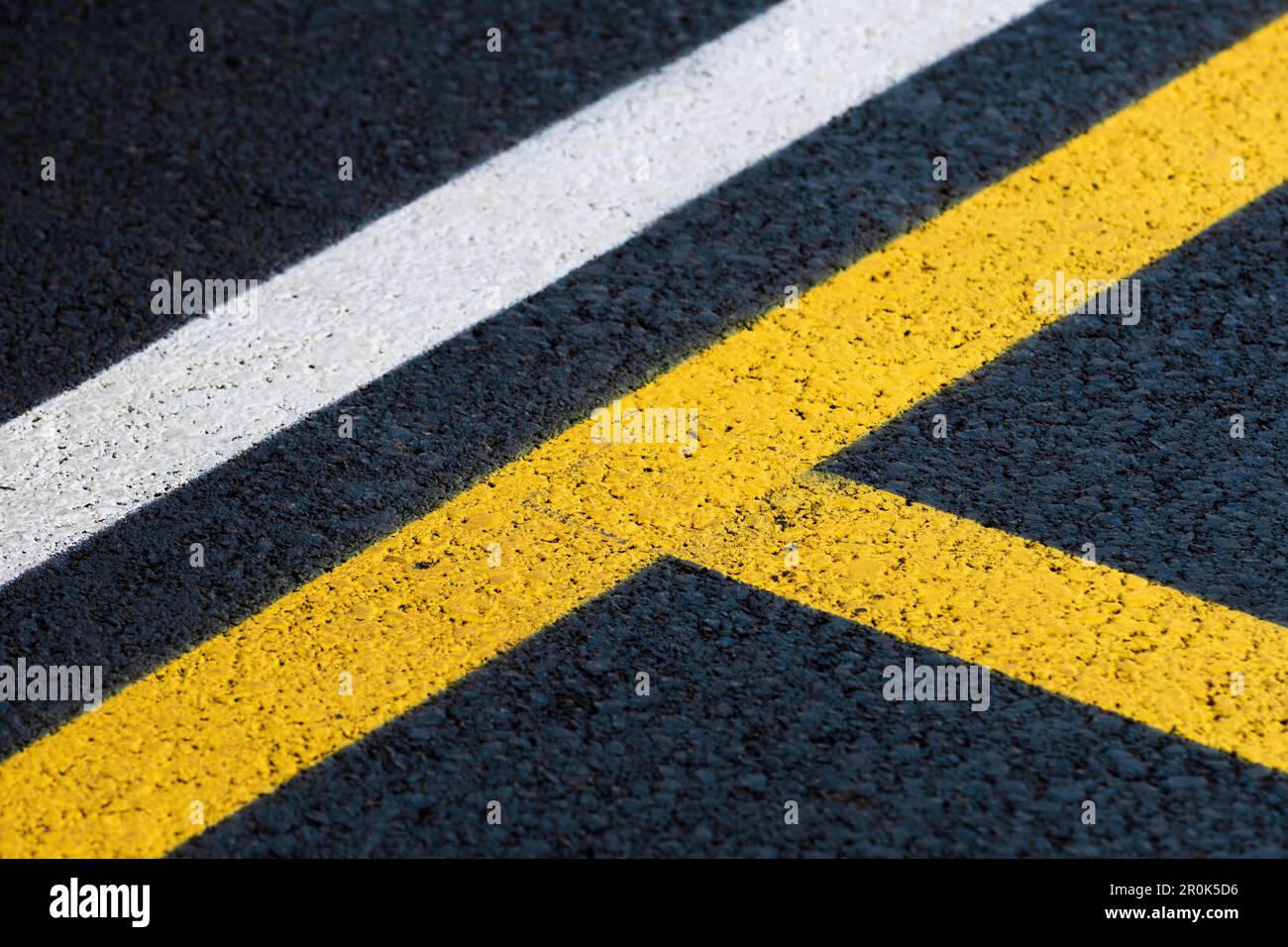 Road marking on brand new asphalt surface of a parking lot, yellow and ...