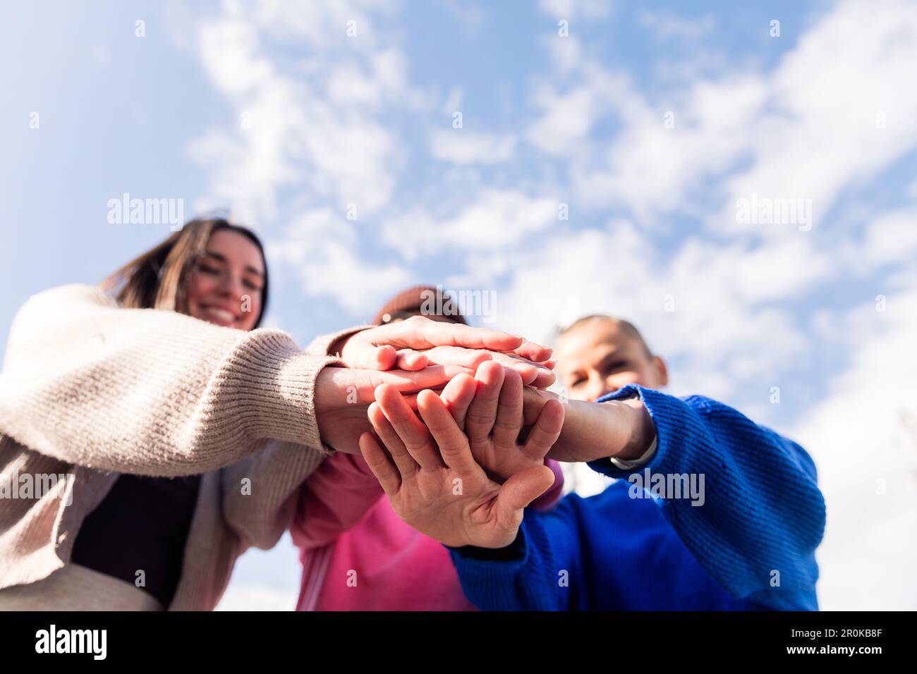 three happy friends holding hands in unity Stock Photo - Alamy