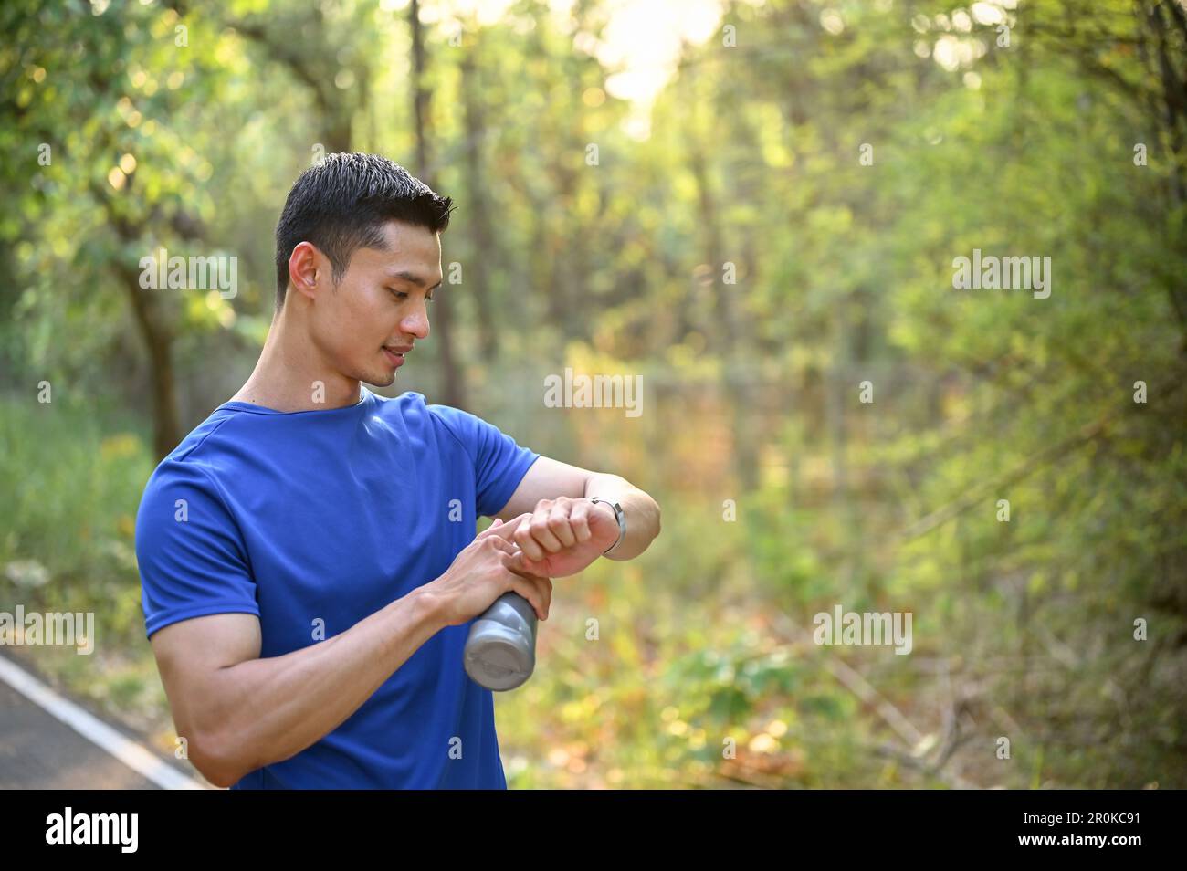 Handsome millennial Asian male runner in sportswear is looking at his ...
