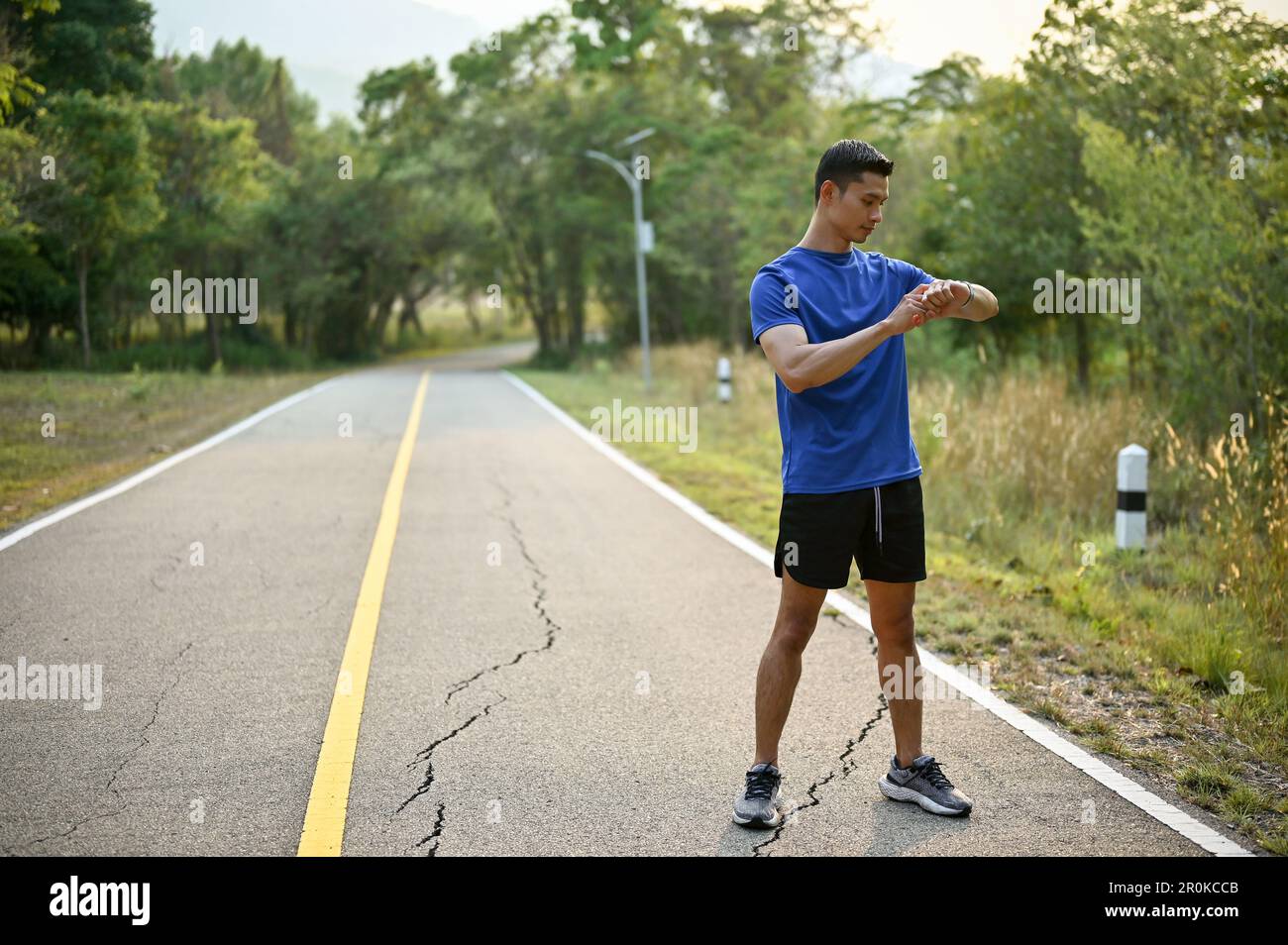 Handsome Asian athletic man in sportswear checking his heart rate and ...