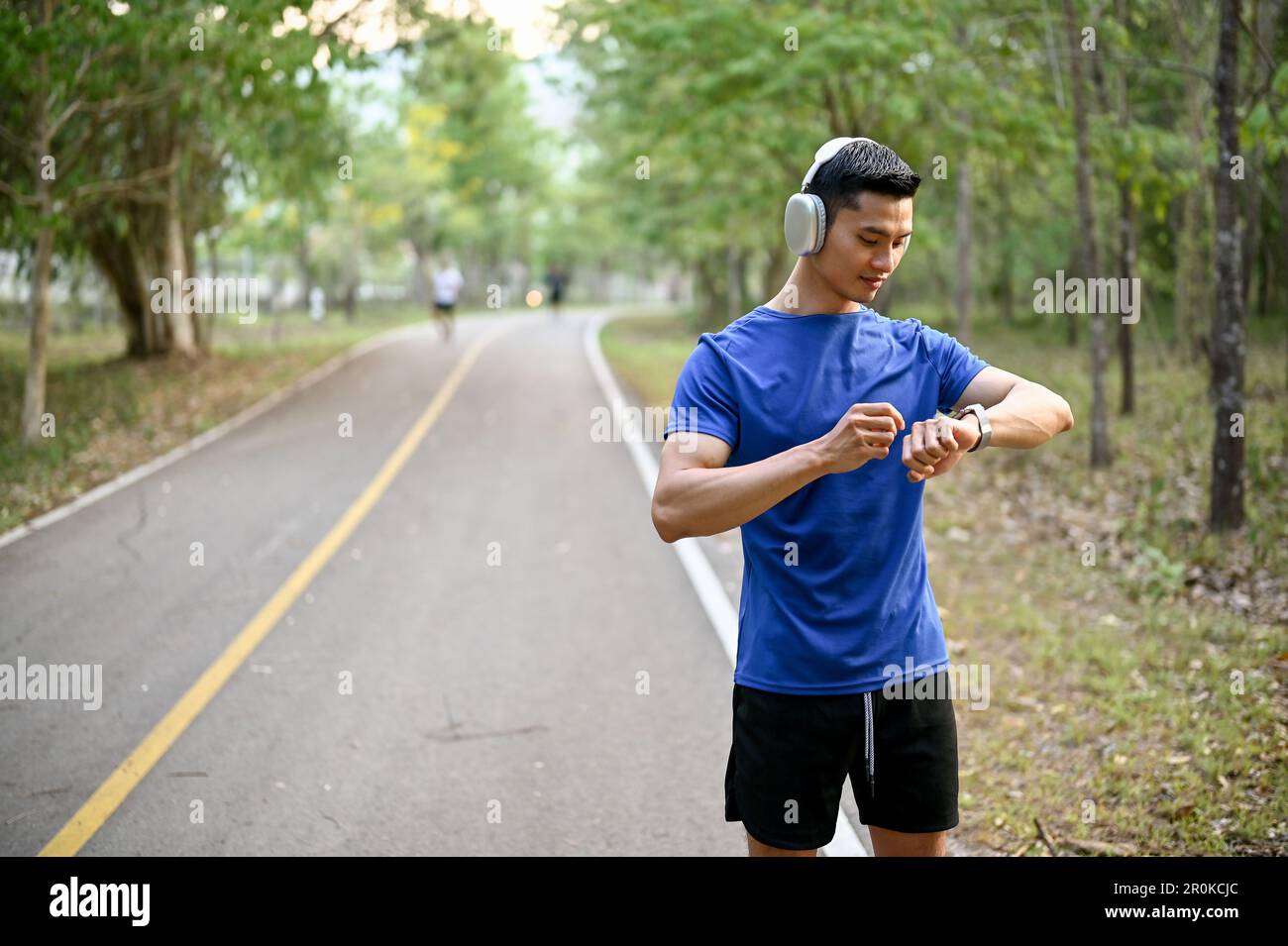 Handsome millennial Asian man wearing headphones, checking his heart ...