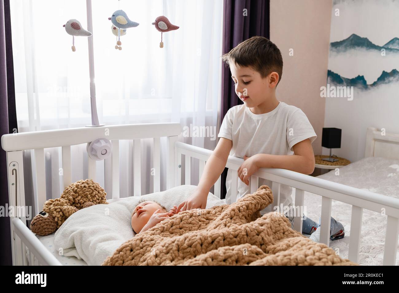 Older brother preschooler age hold hand of newborn infant baby in crib ...