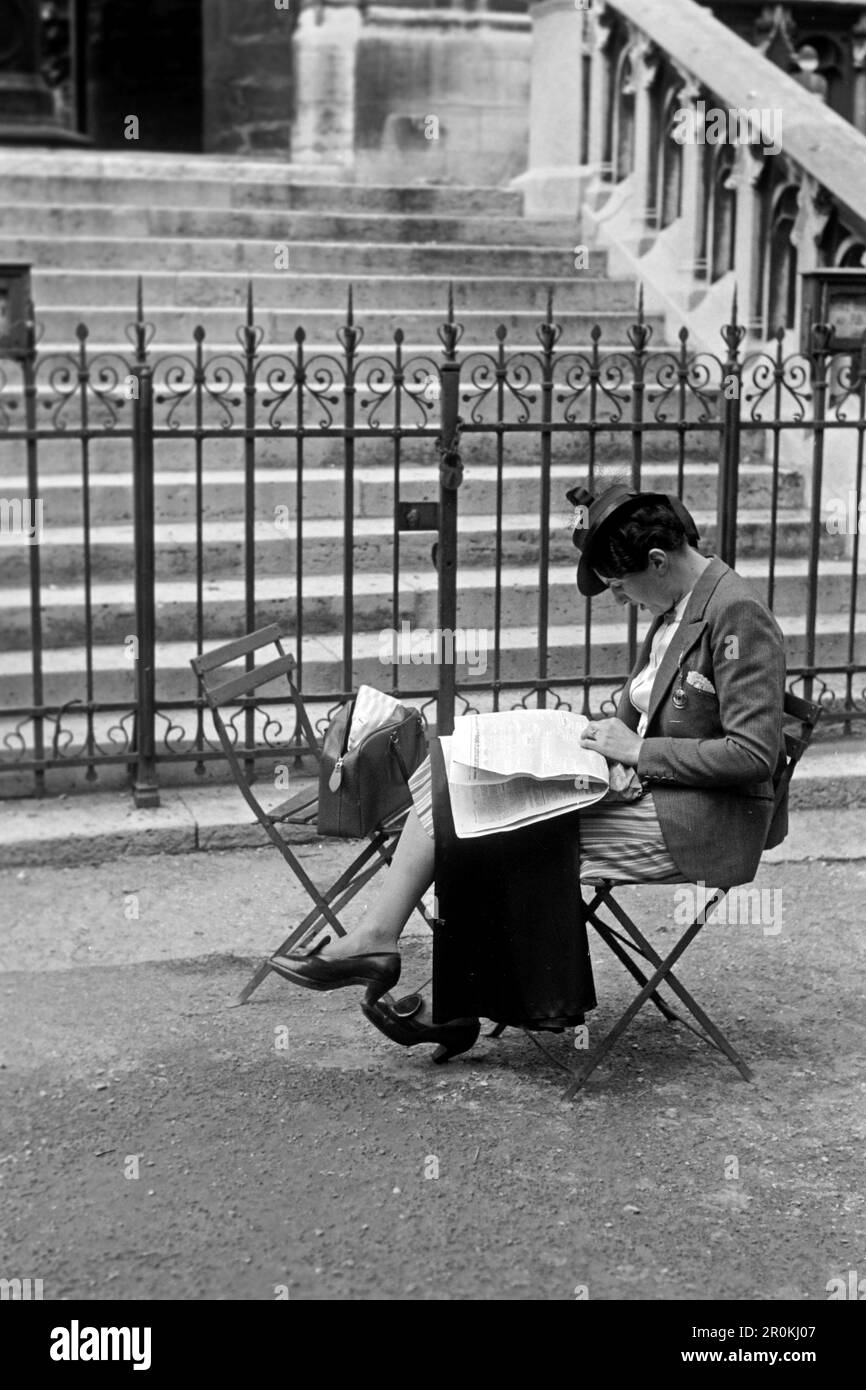 Eine Dame mit Hut liest Zeitung, Paris 1940. A lady with a hat reading ...